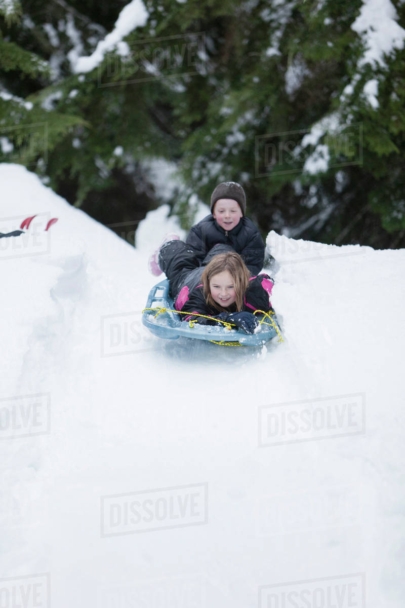 Caucasian children sledding in snow - Royalty-free Stock Photo | Dissolve