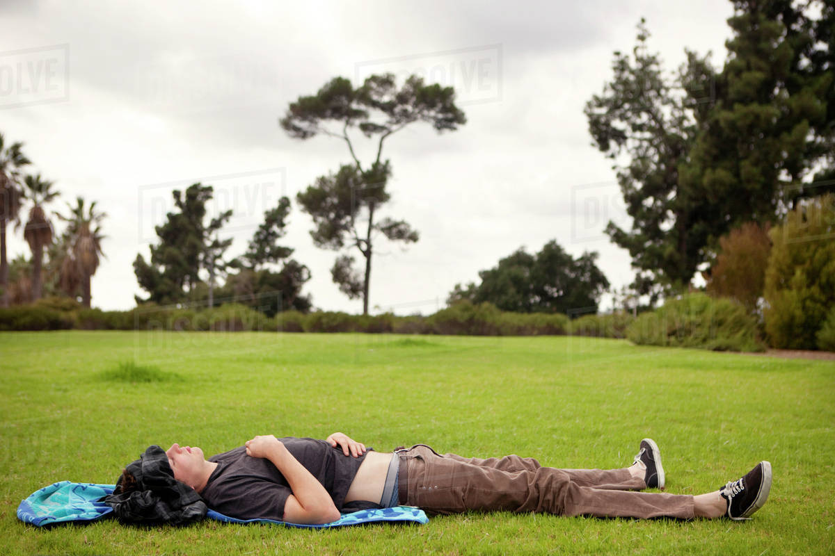 Caucasian man laying in grass in park - Royalty-free Stock Photo | Dissolve