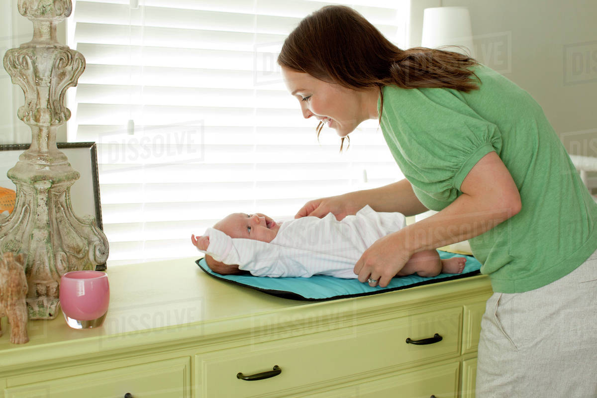 Caucasian mother changing baby daughter - Stock Photo - Dissolve