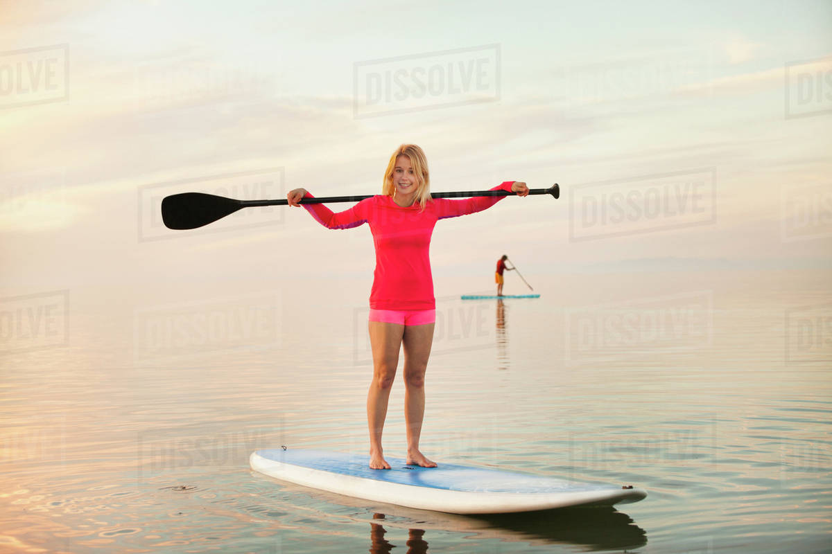 Caucasian woman standing on paddle board - Stock Photo - Dissolve