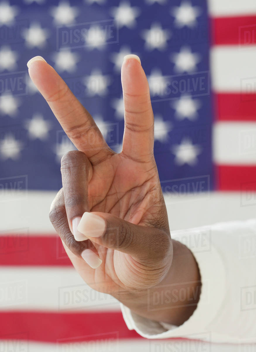 African woman making peace symbol near American flag - Royalty-free ...