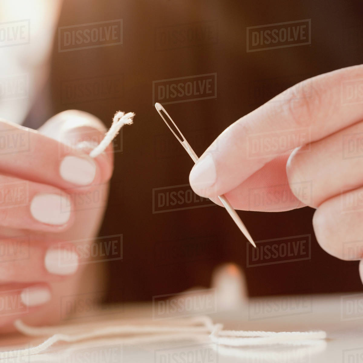 Woman stringing frayed thread through needle - Royalty-free Stock Photo ...