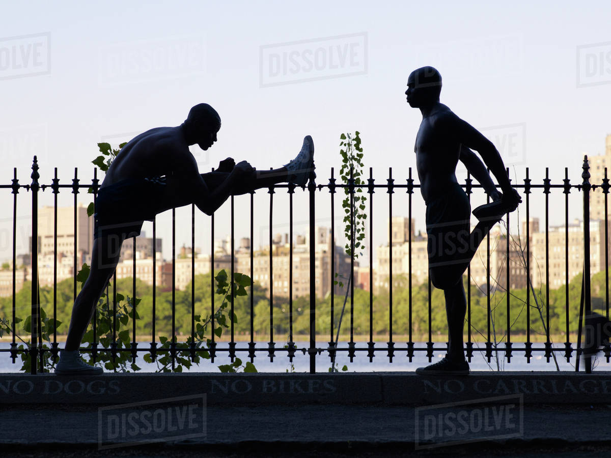 African men stretching on railing - Stock Photo - Dissolve