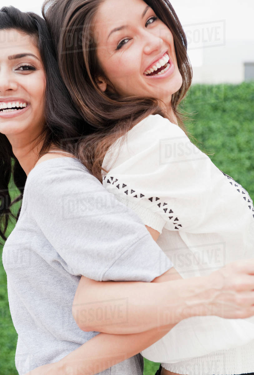 Friends linking arms back to back - Stock Photo - Dissolve