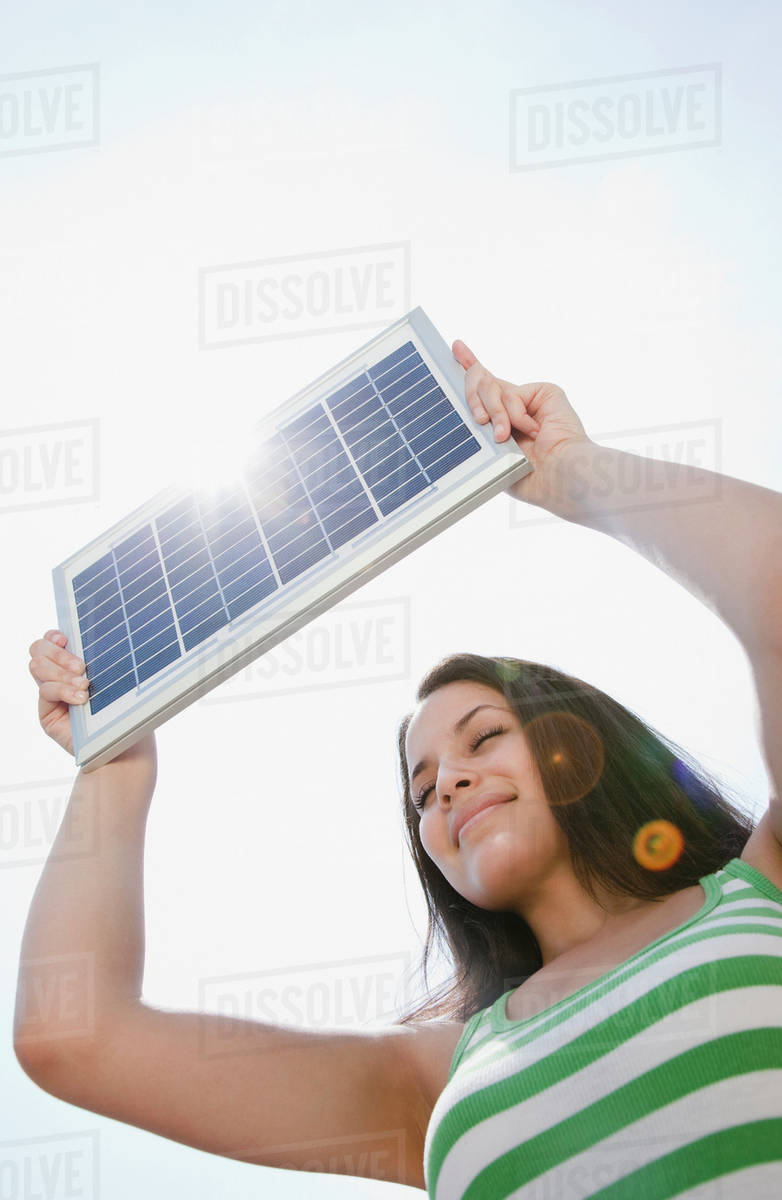 Mixed race woman holding solar panel - Royalty-free Stock Photo | Dissolve