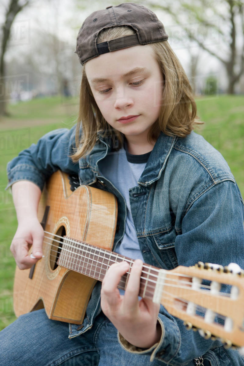 Caucasian boy playing acoustic guitar - Royalty-free Stock Photo | Dissolve