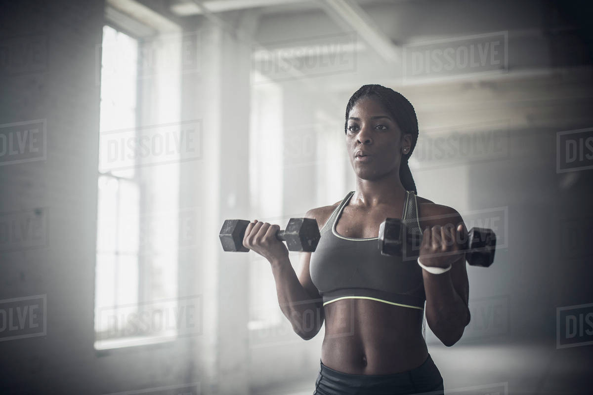 Black woman lifting weights in dark gym - Royalty-free Stock Photo ...