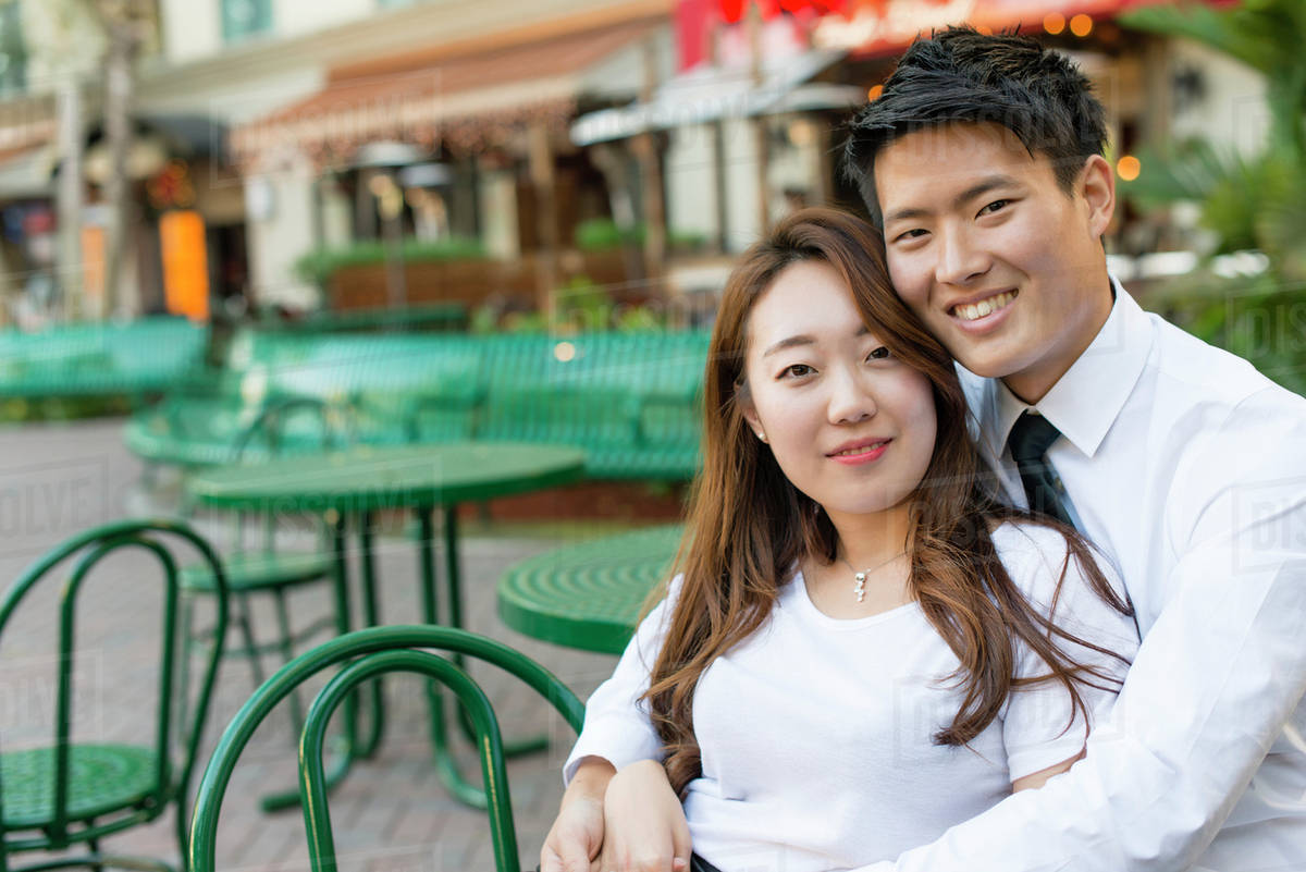 Korean couple hugging at sidewalk cafe - Stock Photo - Dissolve