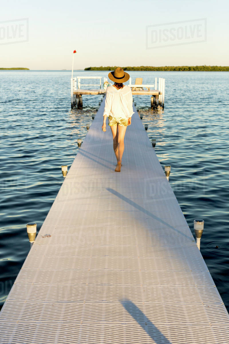 Caucasian woman walking on pier over water - Royalty-free Stock Photo ...