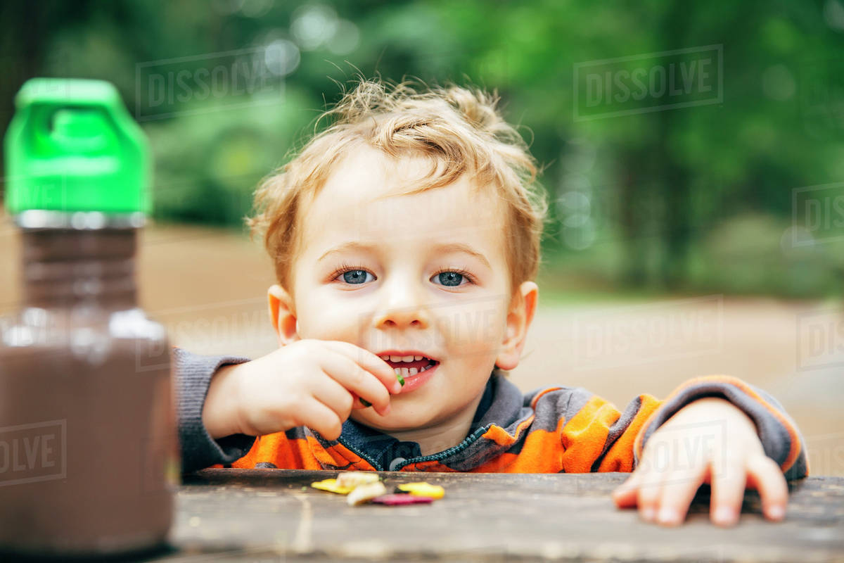 Caucasian boy eating snack at picnic table - Royalty-free Stock Photo ...