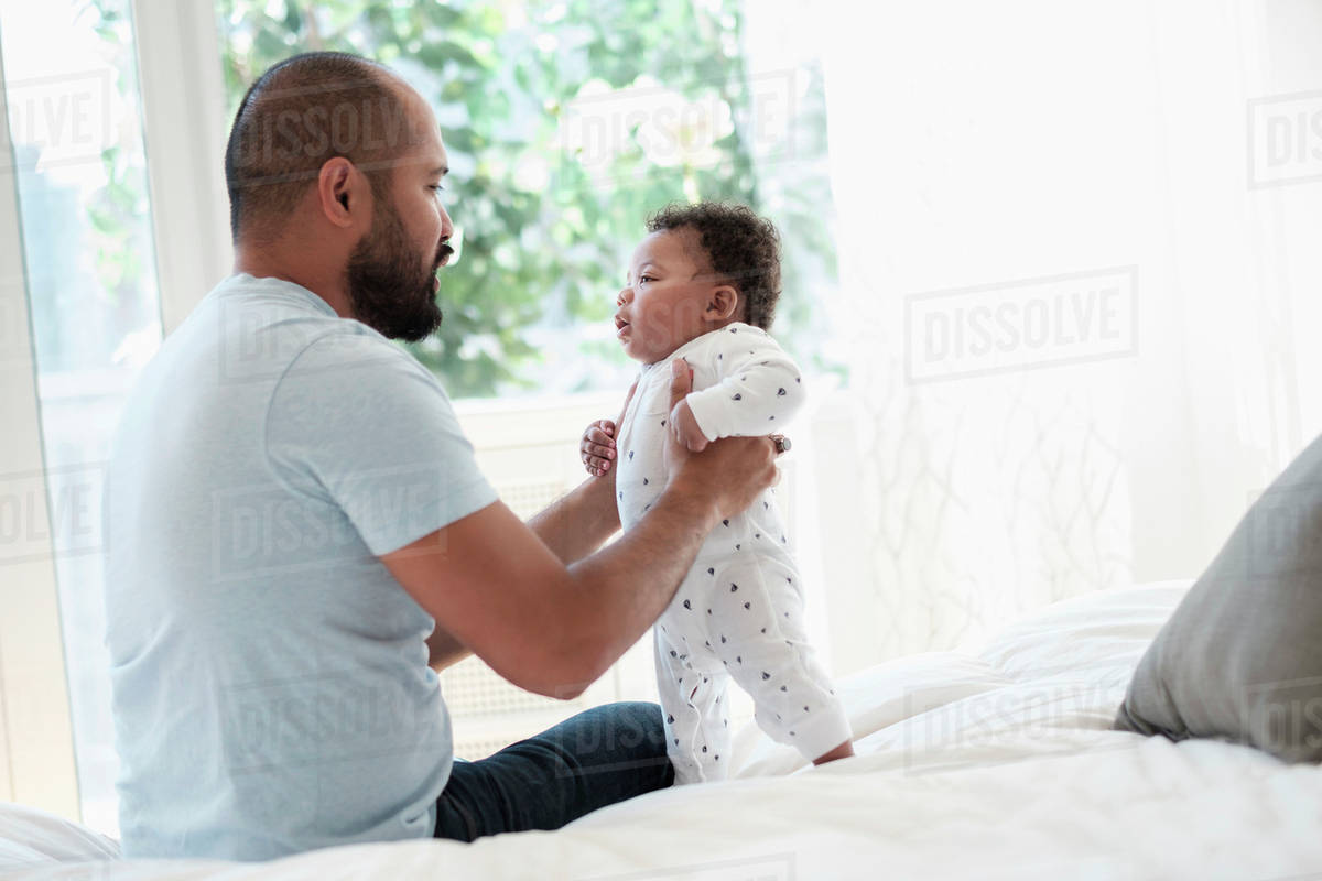Father playing with baby son on bed - Royalty-free Stock Photo | Dissolve