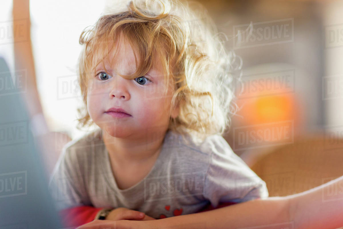 Caucasian baby boy peering at computer screen - Stock Photo - Dissolve