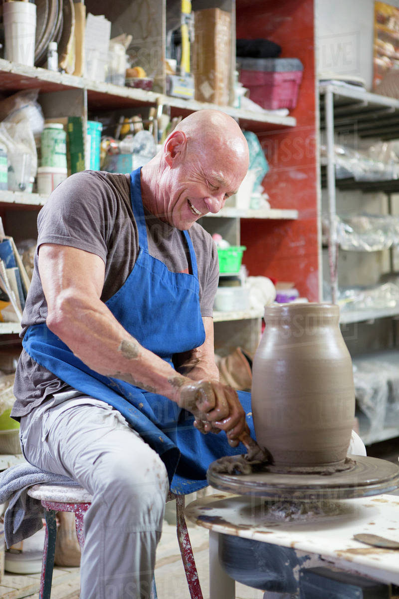 Older Caucasian man forming pottery on wheel in ceramics studio ...