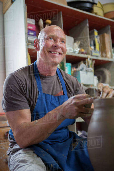 Older Caucasian man forming pottery on wheel in ceramics studio ...