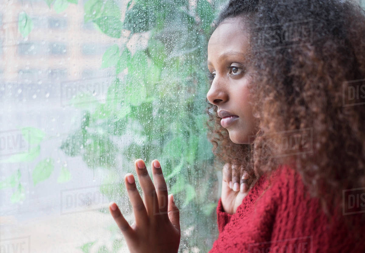 Black woman looking out rainy window - Royalty-free Stock Photo | Dissolve