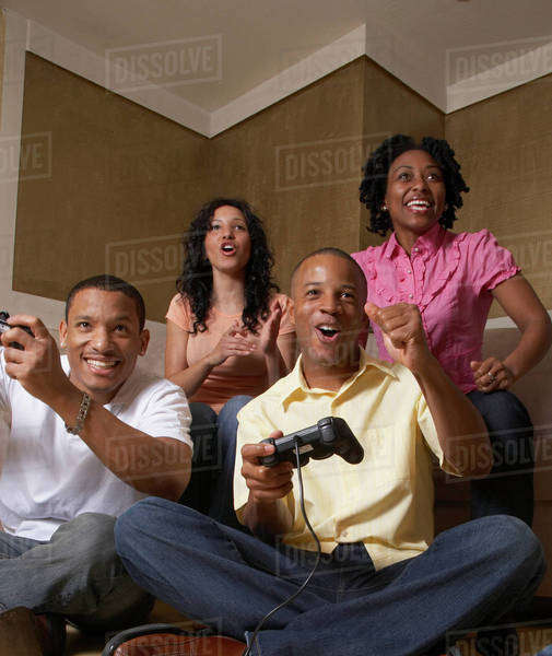 Multi-ethnic friends playing video games - Stock Photo - Dissolve