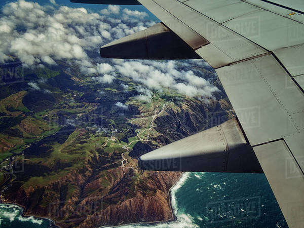 Aerial view of airplane wing flying over coastline - Stock Photo - Dissolve