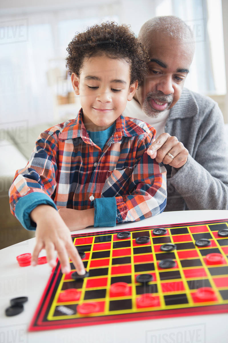 Mixed race grandfather and grandson playing checkers - Royalty-free ...