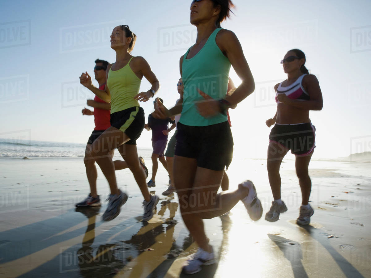 Multi-ethnic runners racing at beach - Royalty-free Stock Photo | Dissolve