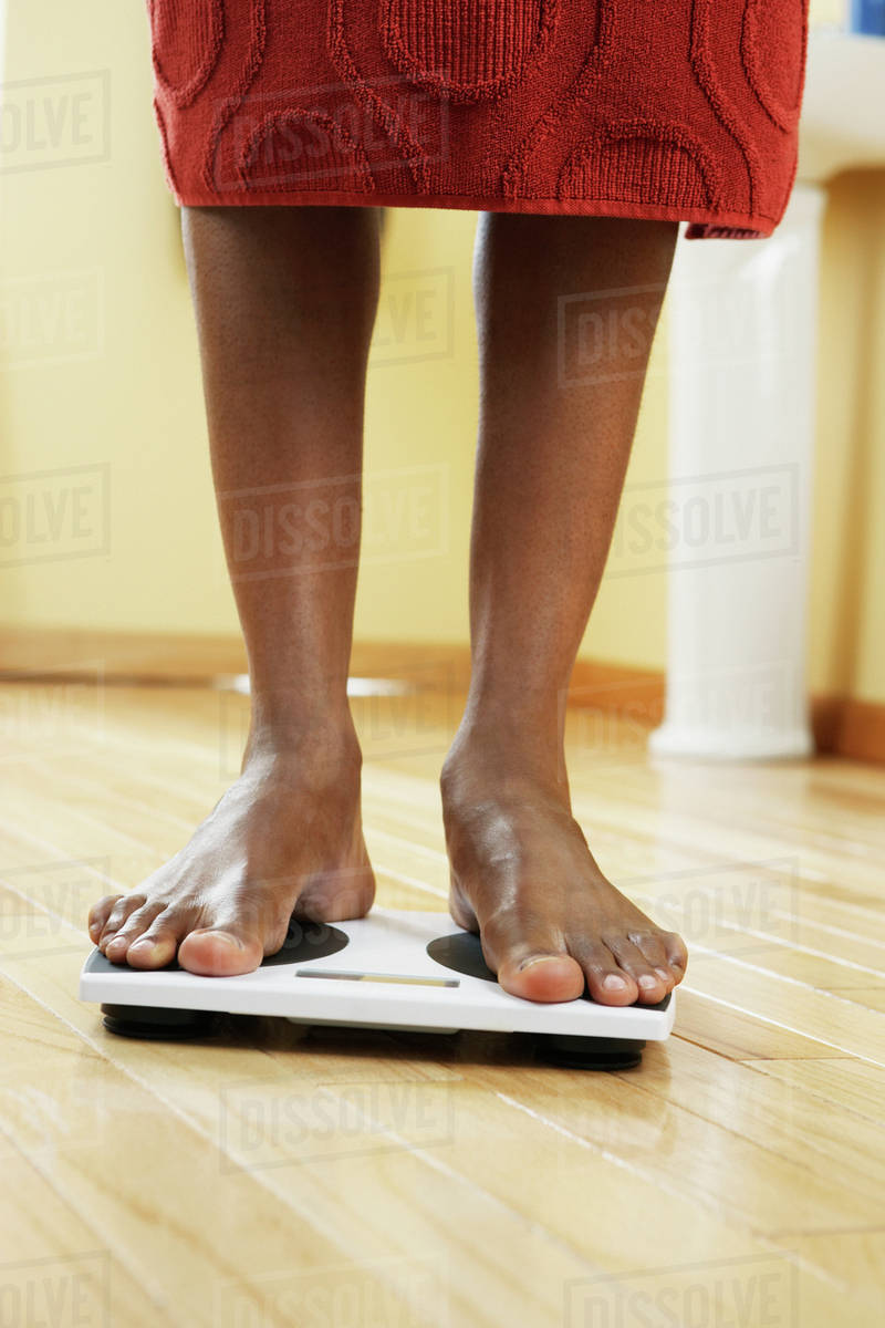 African man standing on scale - Stock Photo - Dissolve