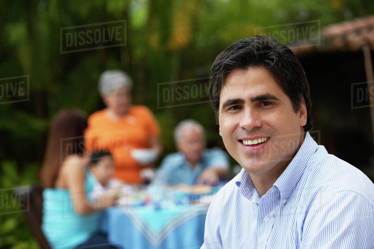 Hispanic man with family in background - Stock Photo - Dissolve