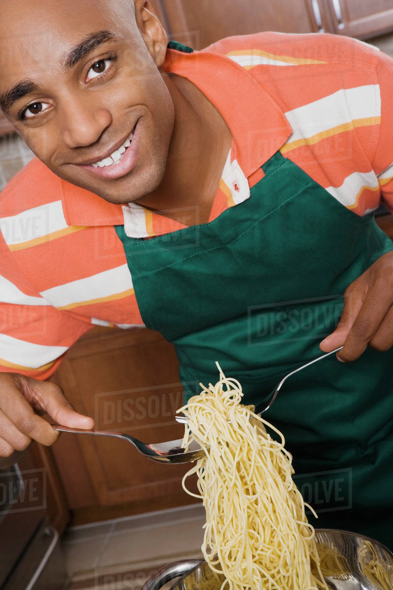 African man serving spaghetti - Royalty-free Stock Photo | Dissolve