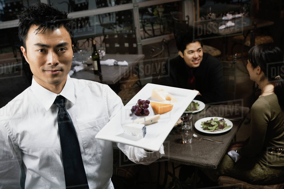 Asian waiter carrying plate of food - Stock Photo - Dissolve