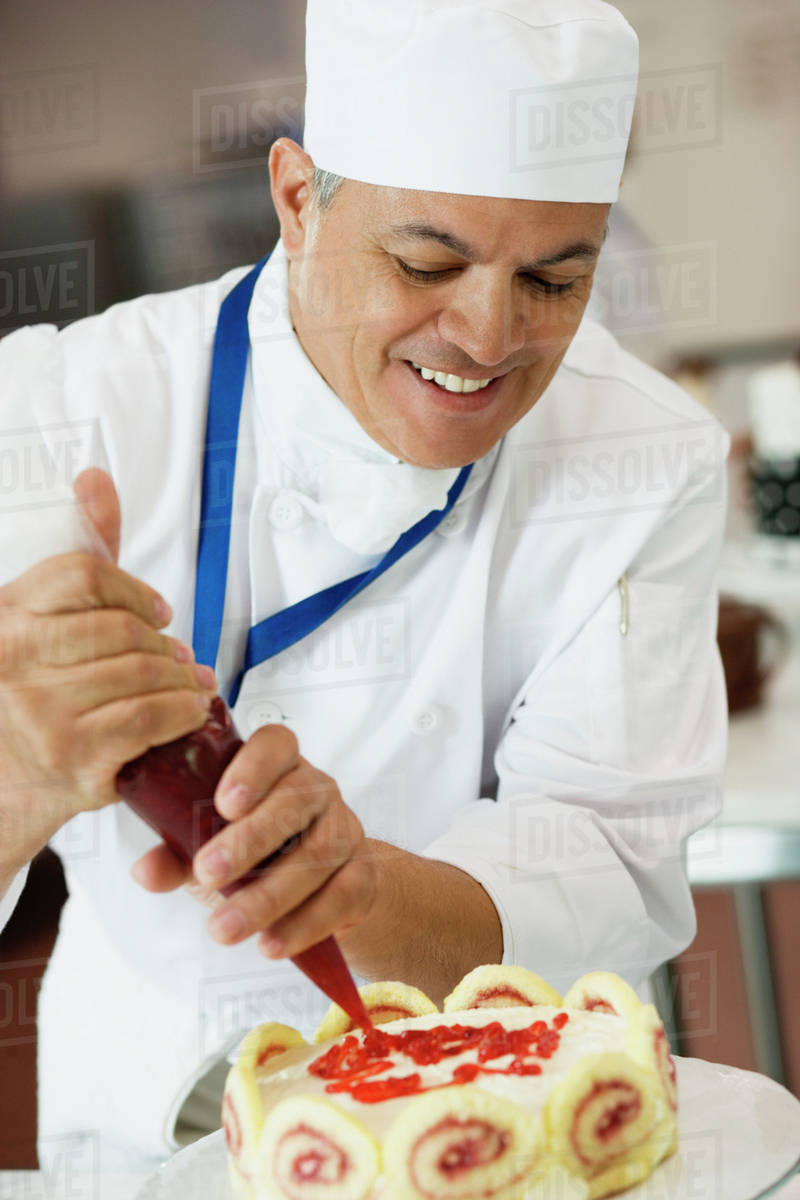 Hispanic male pastry chef decorating cake - Royalty-free Stock Photo ...