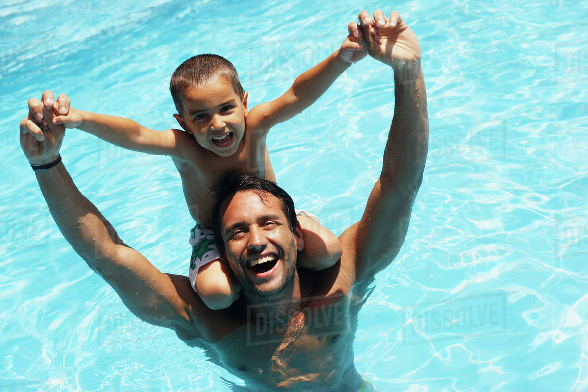 Father giving son piggyback ride in swimming pool - Stock Photo - Dissolve