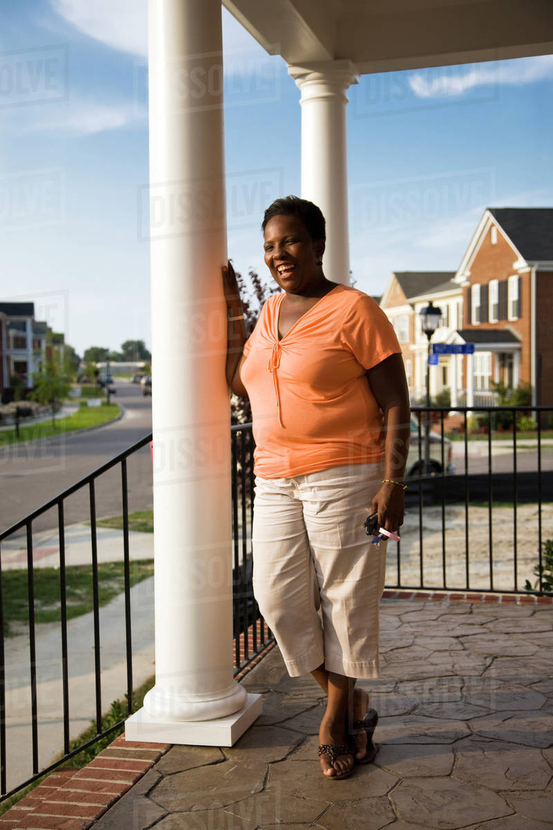 African woman smiling on front stoop of house - Royalty-free Stock ...