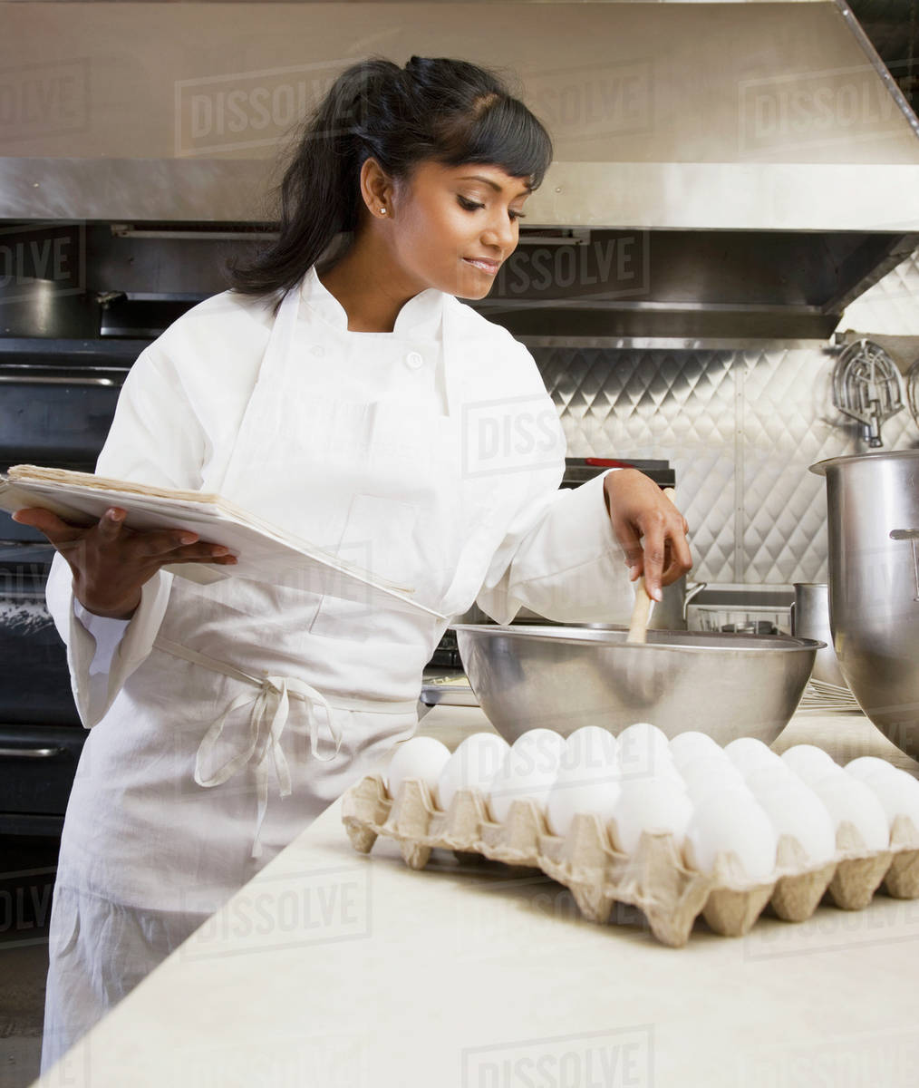 Mixed Race female baker mixing batter - Stock Photo - Dissolve