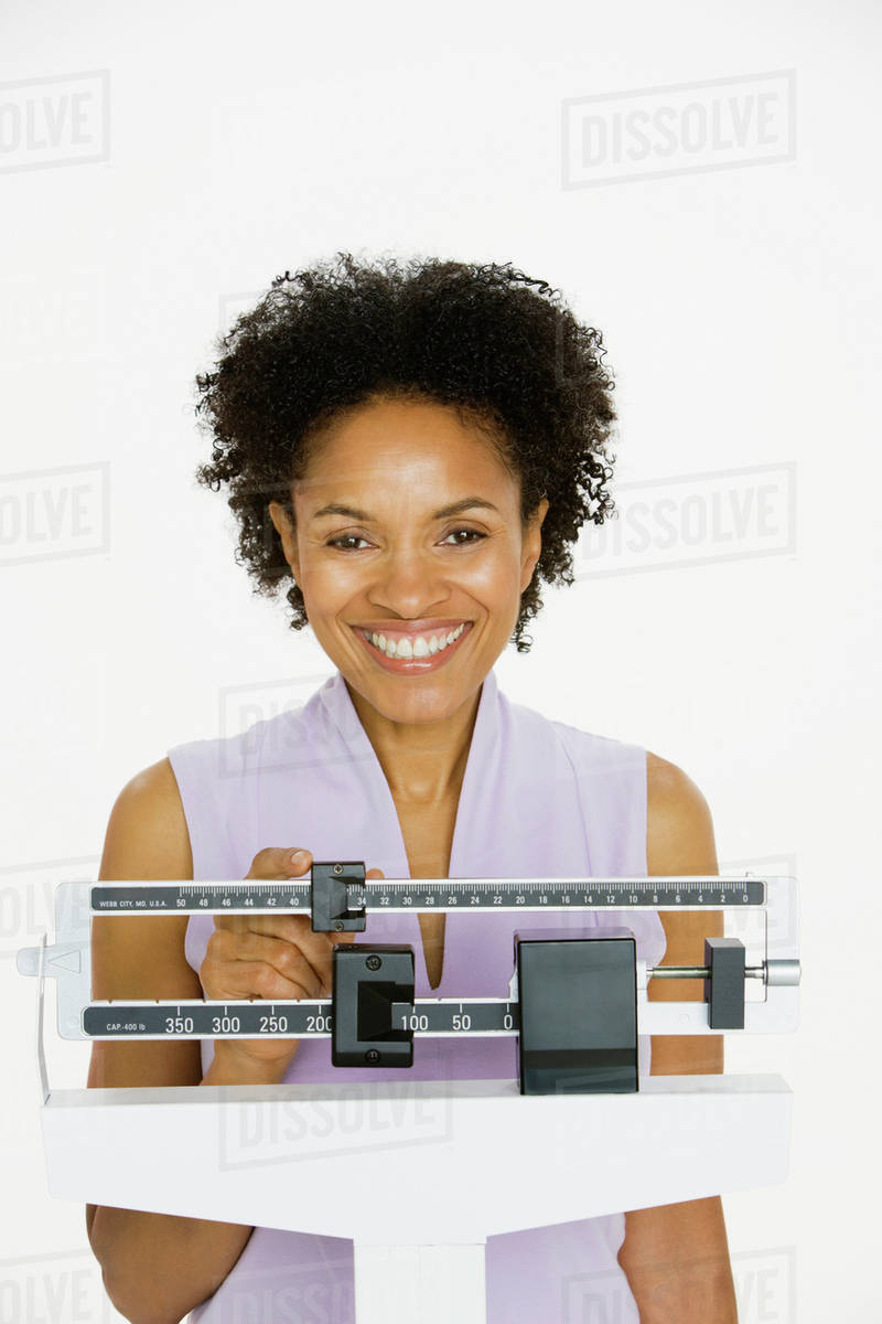 African woman weighing herself on scale - Stock Photo - Dissolve