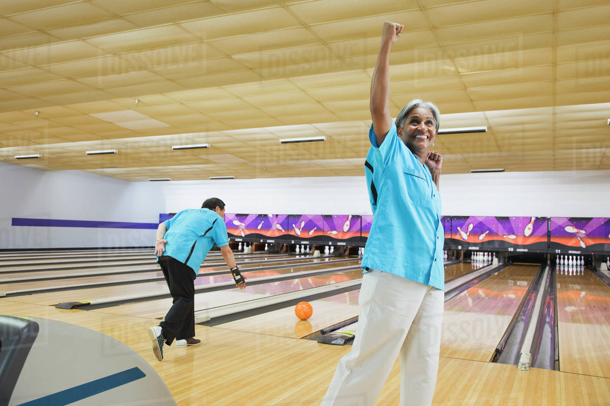 African woman cheering in bowling alley - Stock Photo - Dissolve