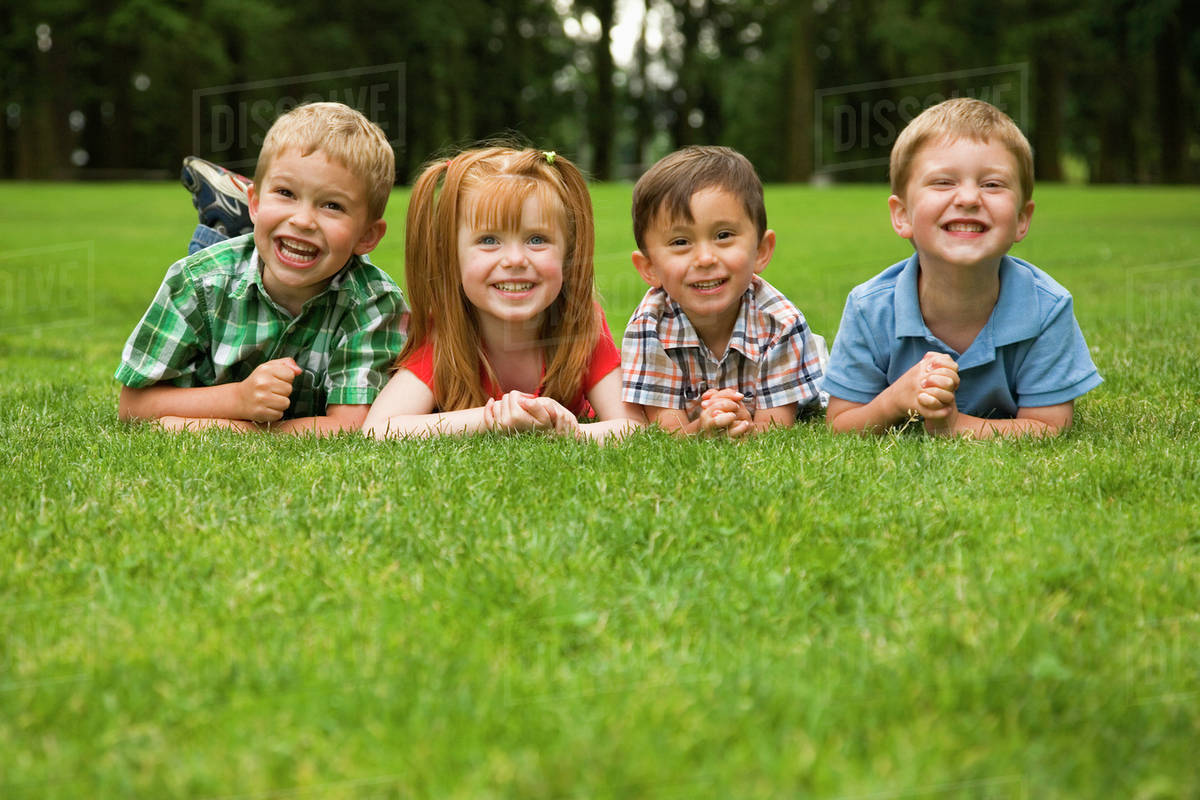Children laying in grass in park - Stock Photo - Dissolve