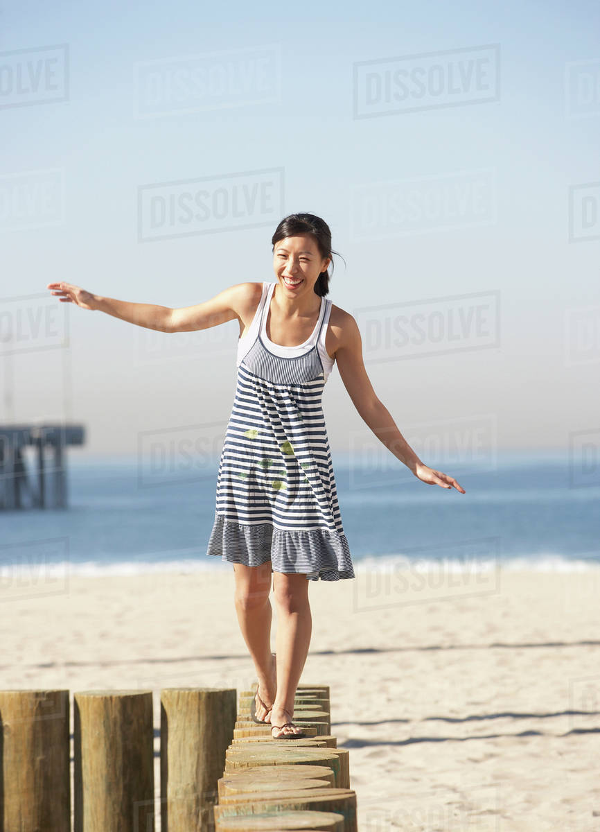 Asian woman balancing on posts at beach - Royalty-free Stock Photo ...
