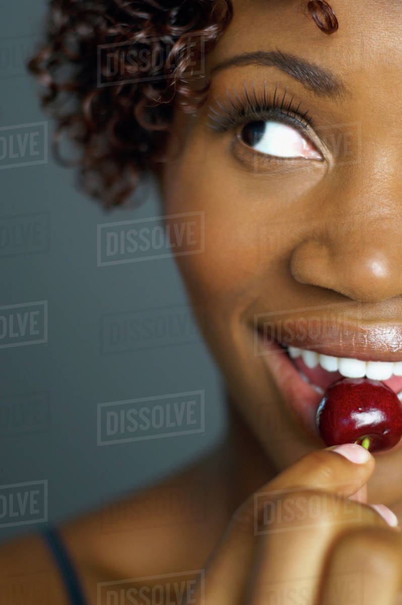 Close up of African woman eating cherry - Stock Photo - Dissolve