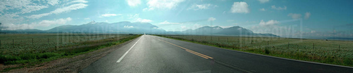 Panoramic view of empty road in rural landscape - Stock Photo - Dissolve