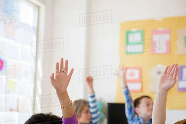 Students raising hands in classroom - Royalty-free Stock Photo | Dissolve