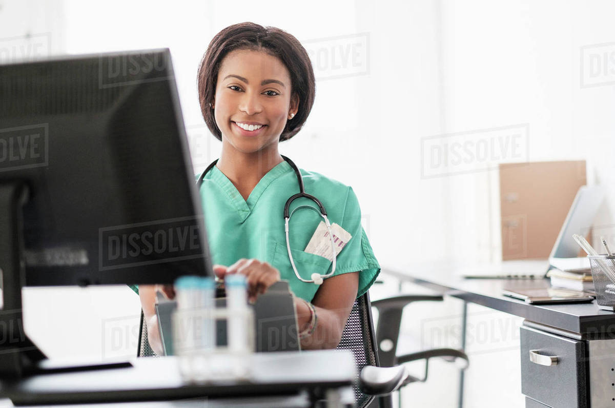 Mixed race nurse smiling at computer - Royalty-free Stock Photo | Dissolve