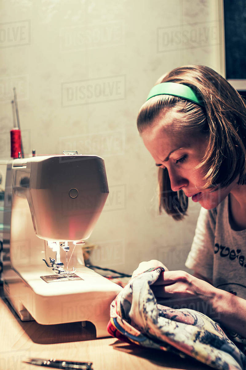 Caucasian woman using sewing machine - Royalty-free Stock Photo | Dissolve