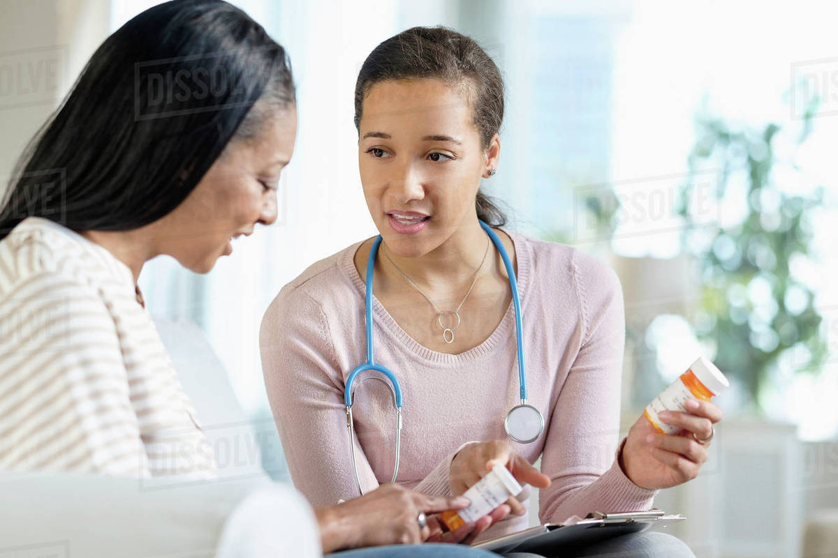 Doctor and patient discussing medication in living room - Royalty-free ...