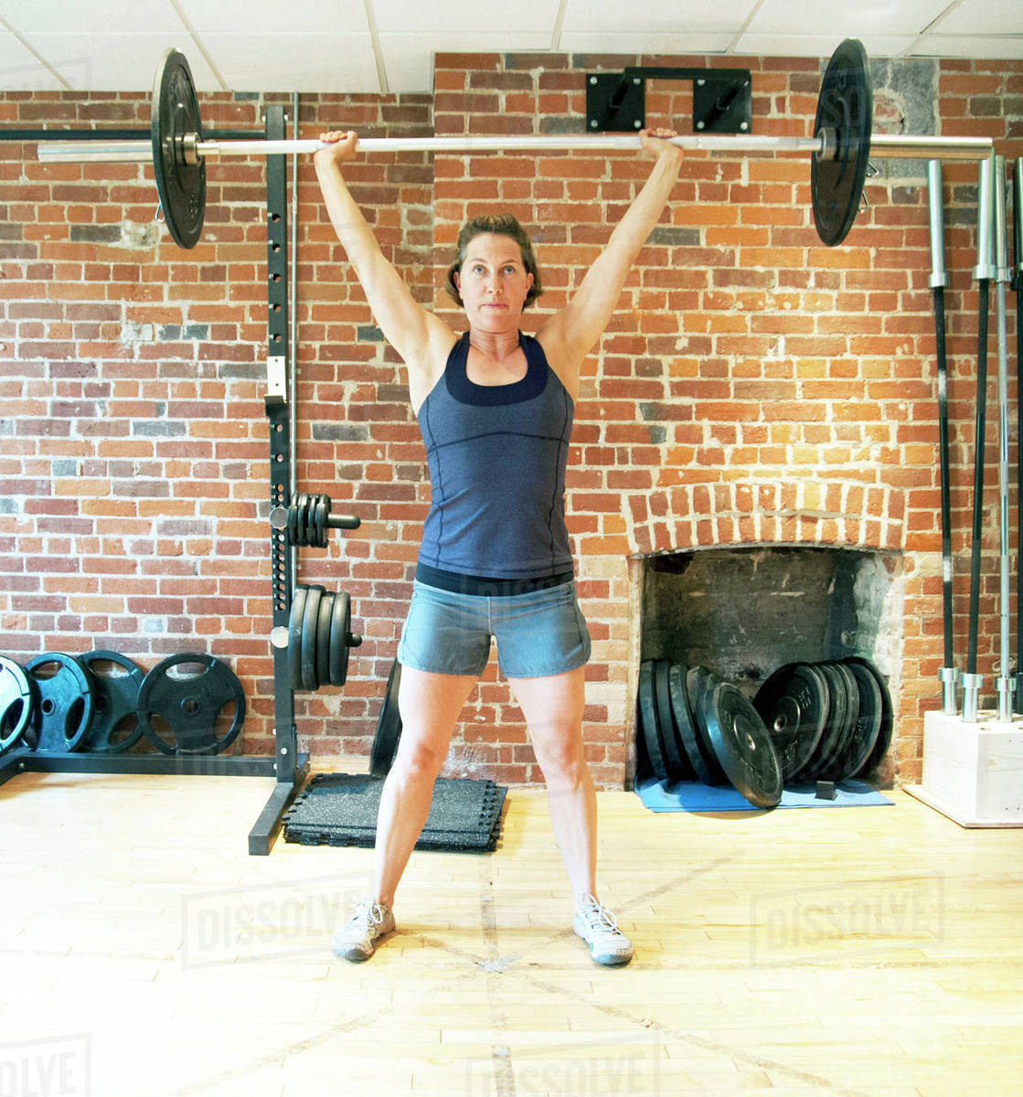 Caucasian woman lifting weights in gymnasium - Stock Photo - Dissolve
