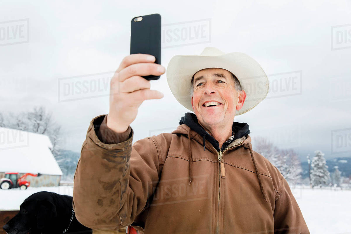Caucasian farmer using cell phone in snowy field - Royalty-free Stock ...