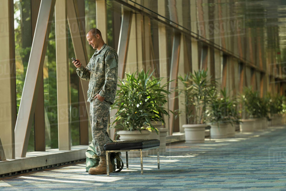 Caucasian soldier using cell phone in airport - Stock Photo - Dissolve