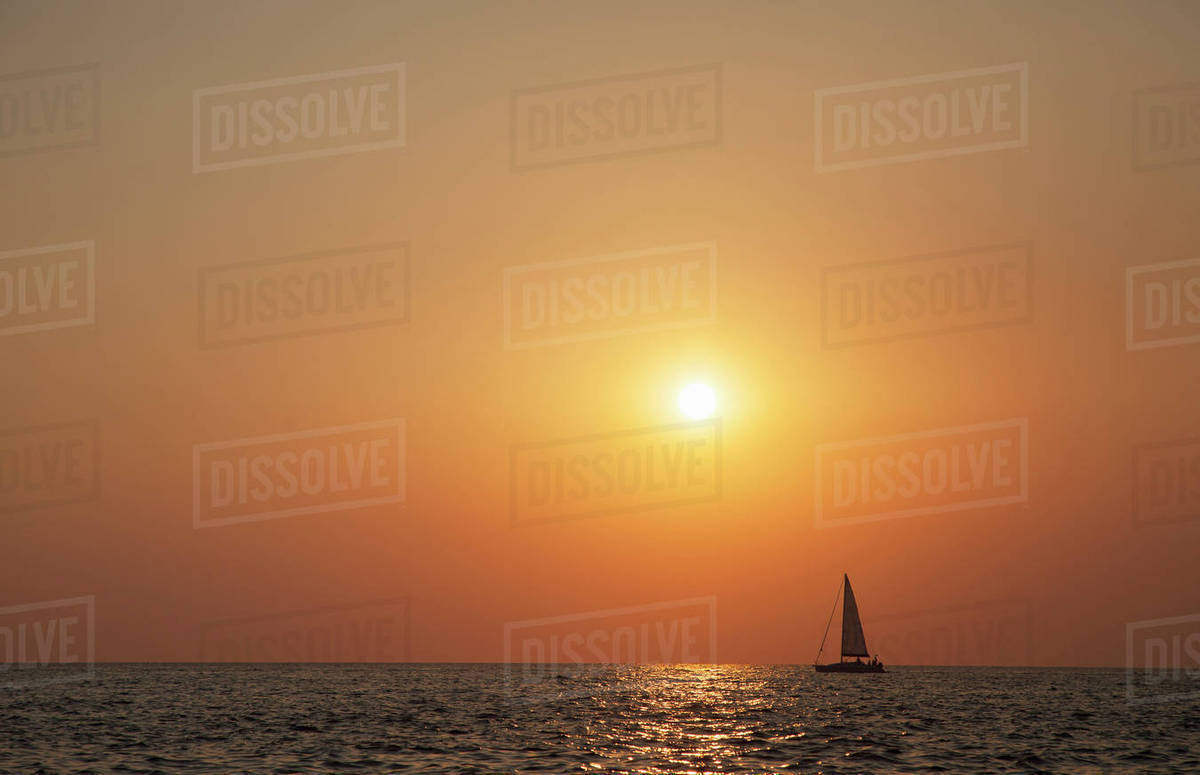 Sailboat sailing on ocean horizon at sunset - Stock Photo - Dissolve