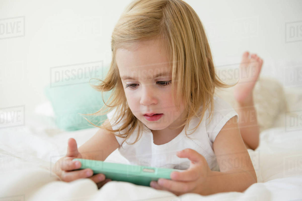 Caucasian girl using cell phone on bed - Royalty-free Stock Photo ...