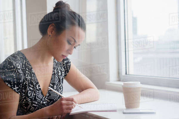 Woman writing in coffee shop - Royalty-free Stock Photo | Dissolve