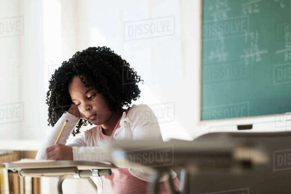 African American student writing in classroom - Stock Photo - Dissolve