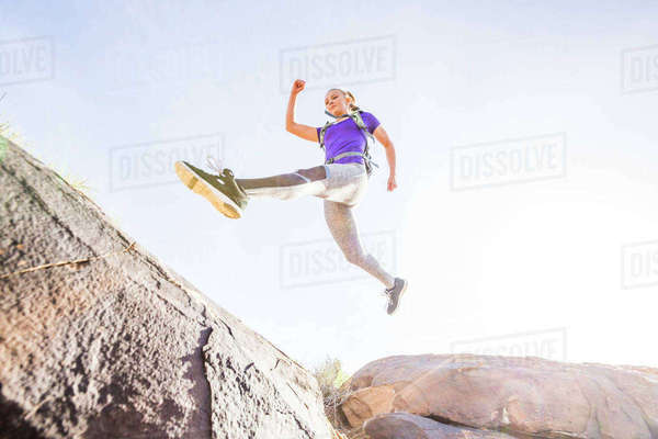 Caucasian woman leaping over boulders - Royalty-free Stock Photo | Dissolve