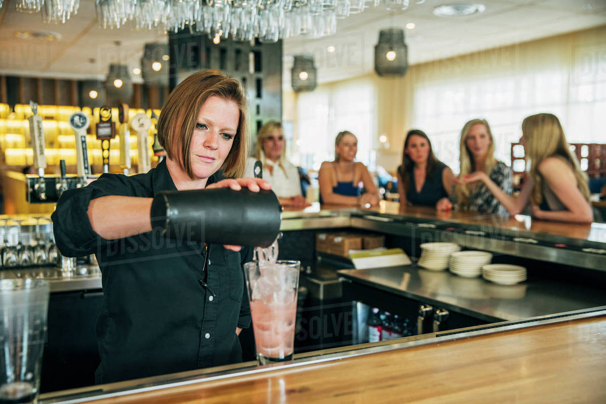 Caucasian bartender pouring cocktail from mixer into glass - Stock ...